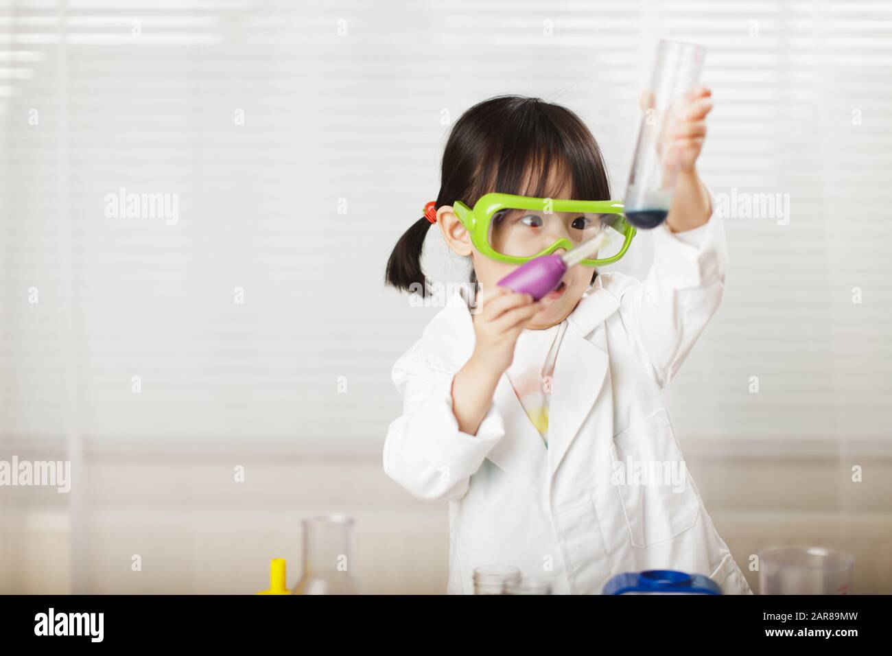 toddler girl pretend play scientist role at home against white ...