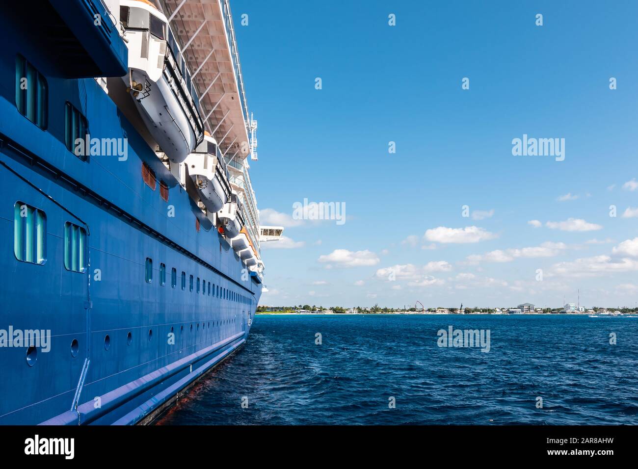 Side of a blue cruise ship that is anchored in the harbor of Grand ...