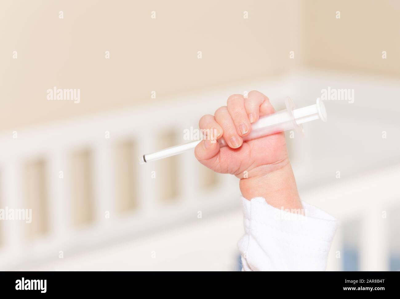 Little baby infant boy hold with small hand medical syringe and crib on ...