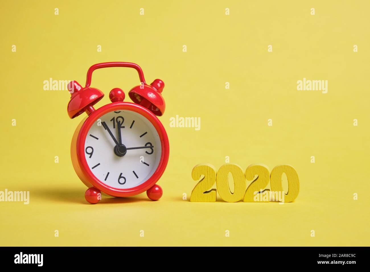 Wooden figures 2020 on a yellow background with red clocks. Close up ...