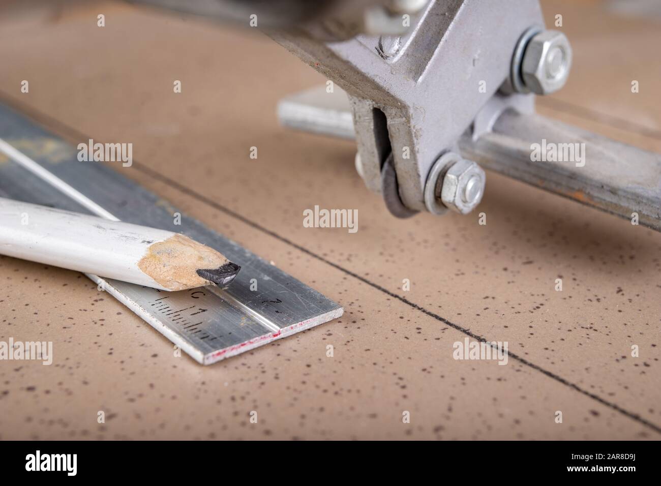 Cutting tiles in a home workshop. Tiling work on a workshop table. Dark ...