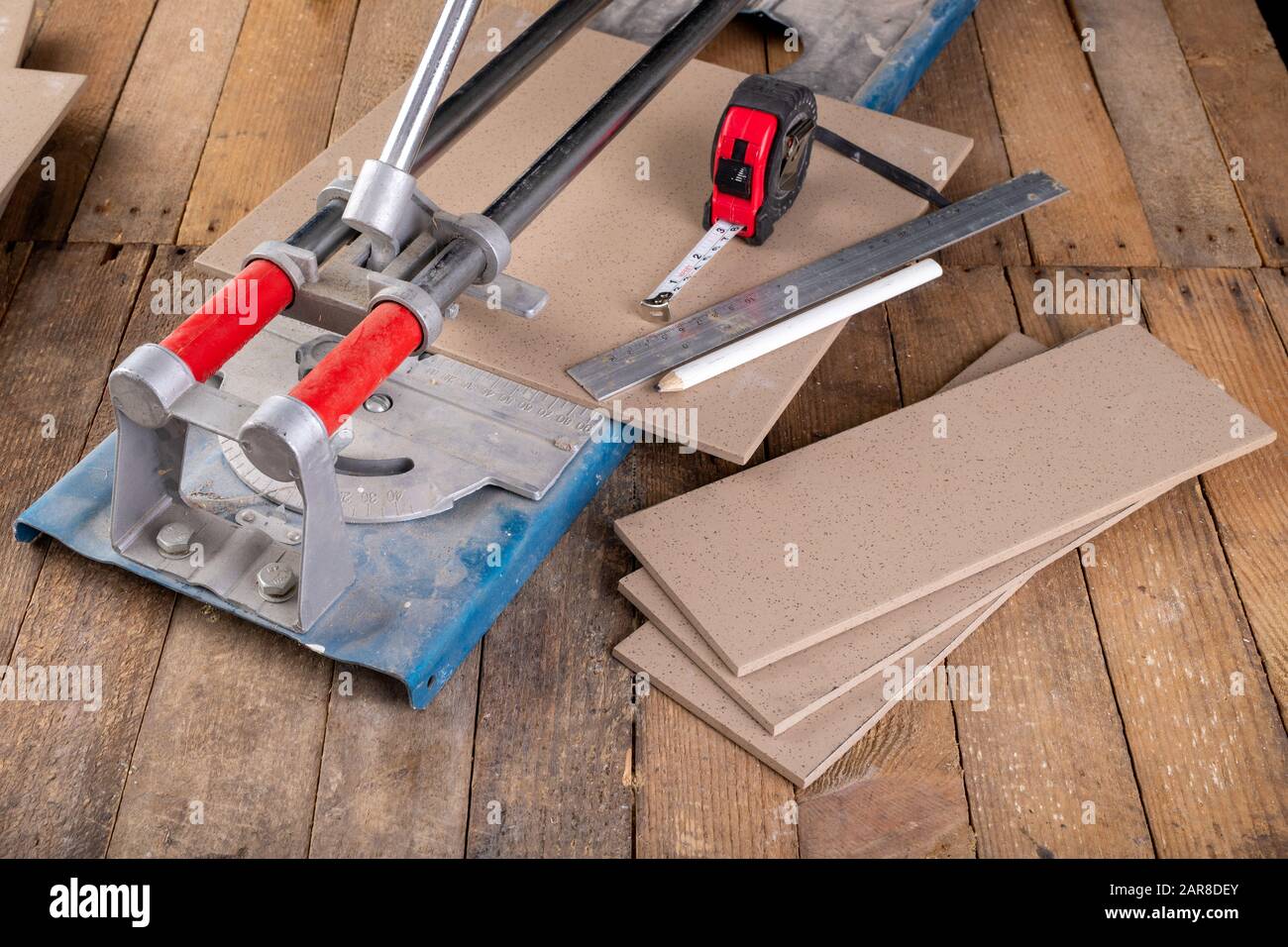 Cutting tiles in a home workshop. Tiling work on a workshop table. Dark ...