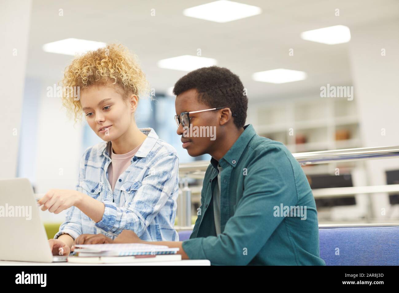 Portrait of two students pointing at laptop screen while working on ...