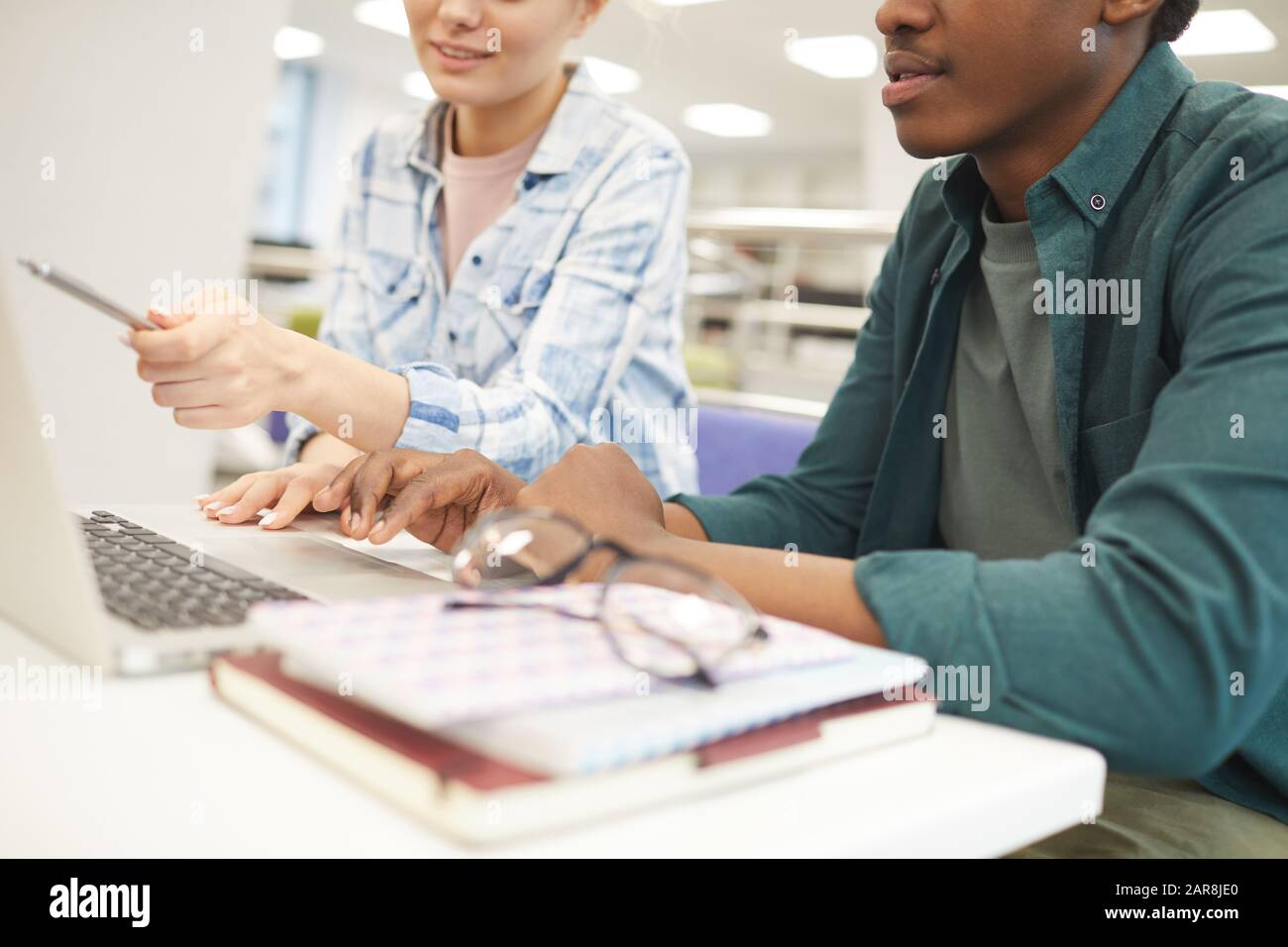 Cropped portrait of two students pointing at laptop screen while ...