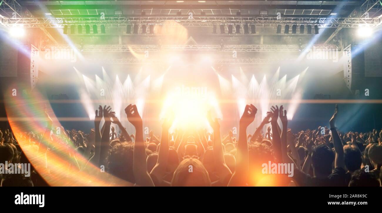 Colourful concert stage inside a venue, people silhouettes are visible ...