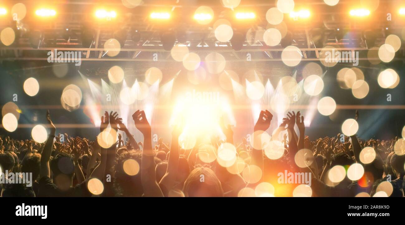 Colourful concert stage inside a venue, people silhouettes are visible ...