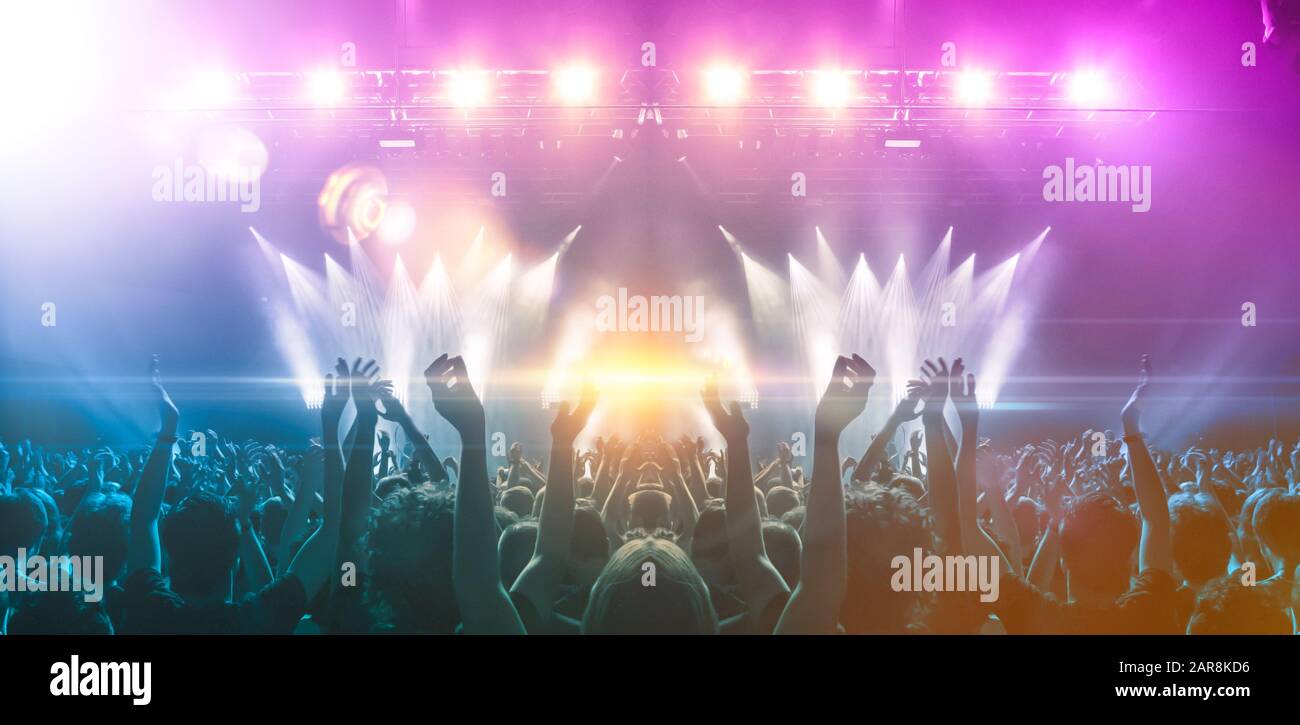 Colourful concert stage inside a venue, people silhouettes are visible ...