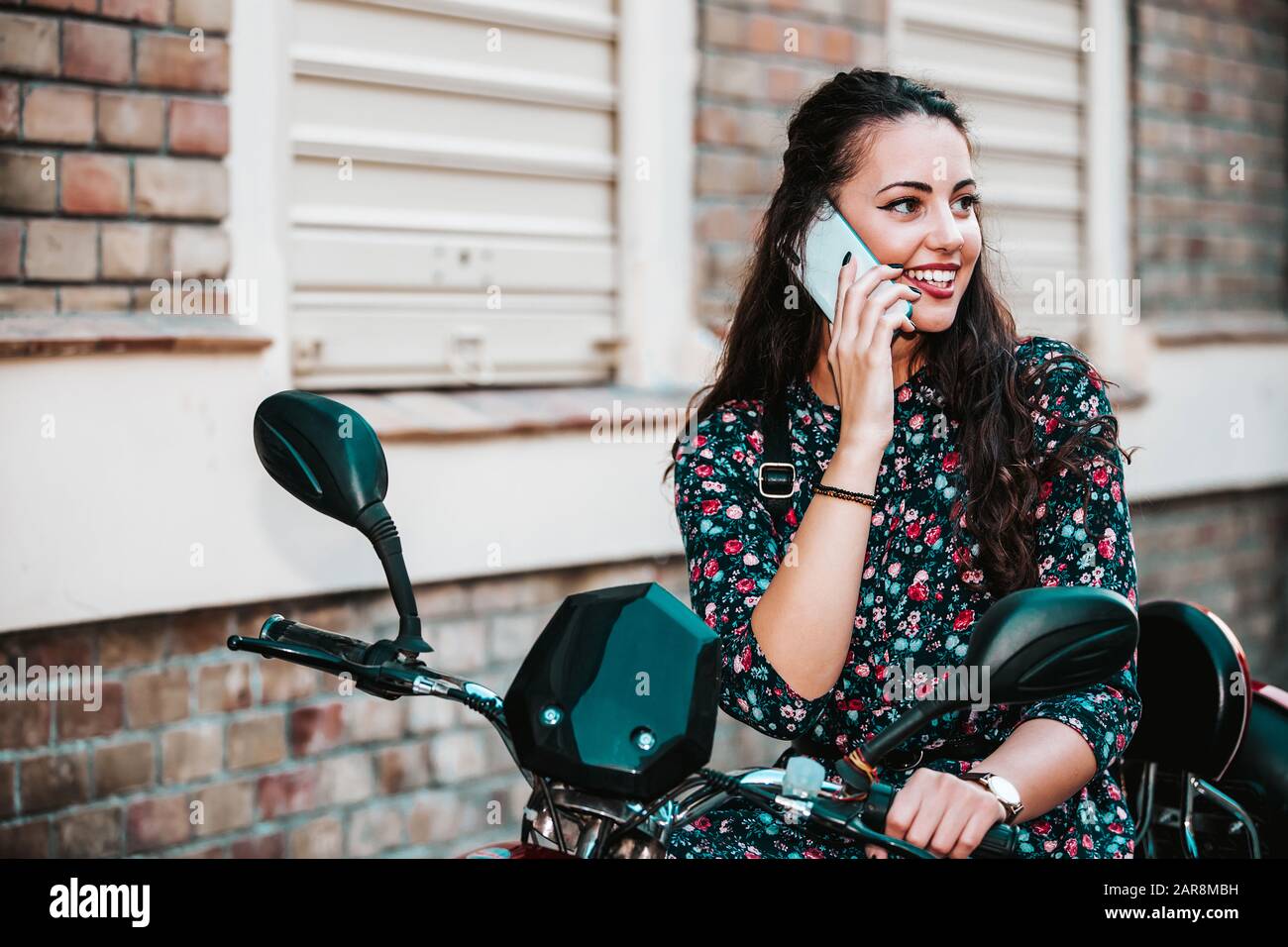 Happy cheerful young woman talking on the phone in the street, smiling ...