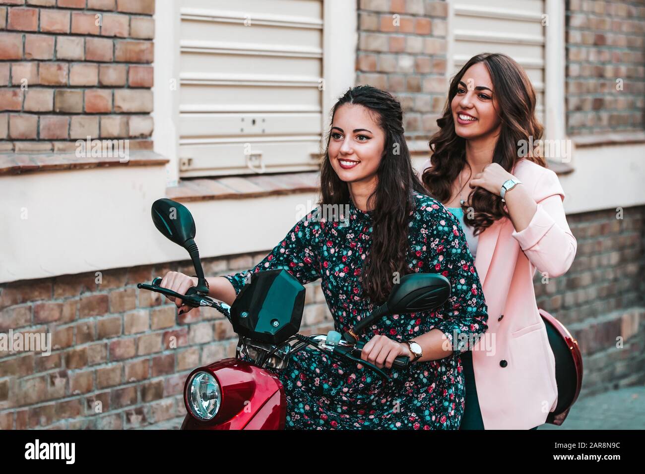 Having great fun together. Two happy young women - friends riding on ...