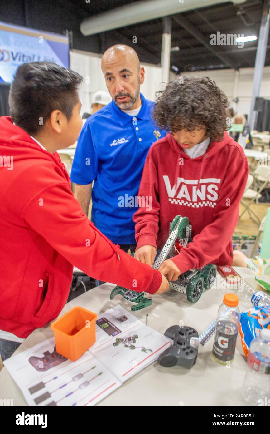 A multiracial high school boys' team assembles a robot at a high tech ...