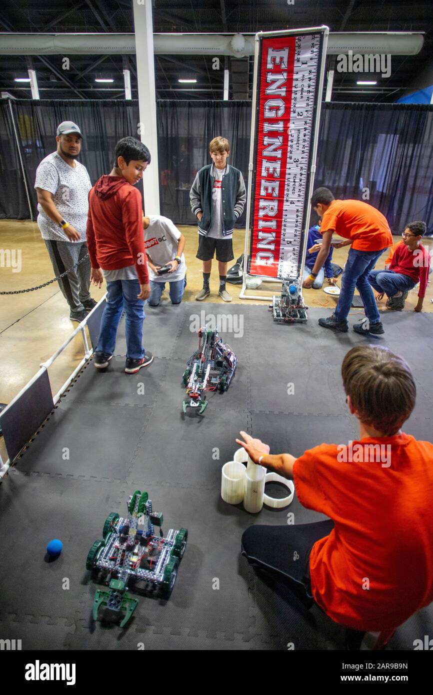 A multiracial high school boys' team demonstrates a robot at a high ...