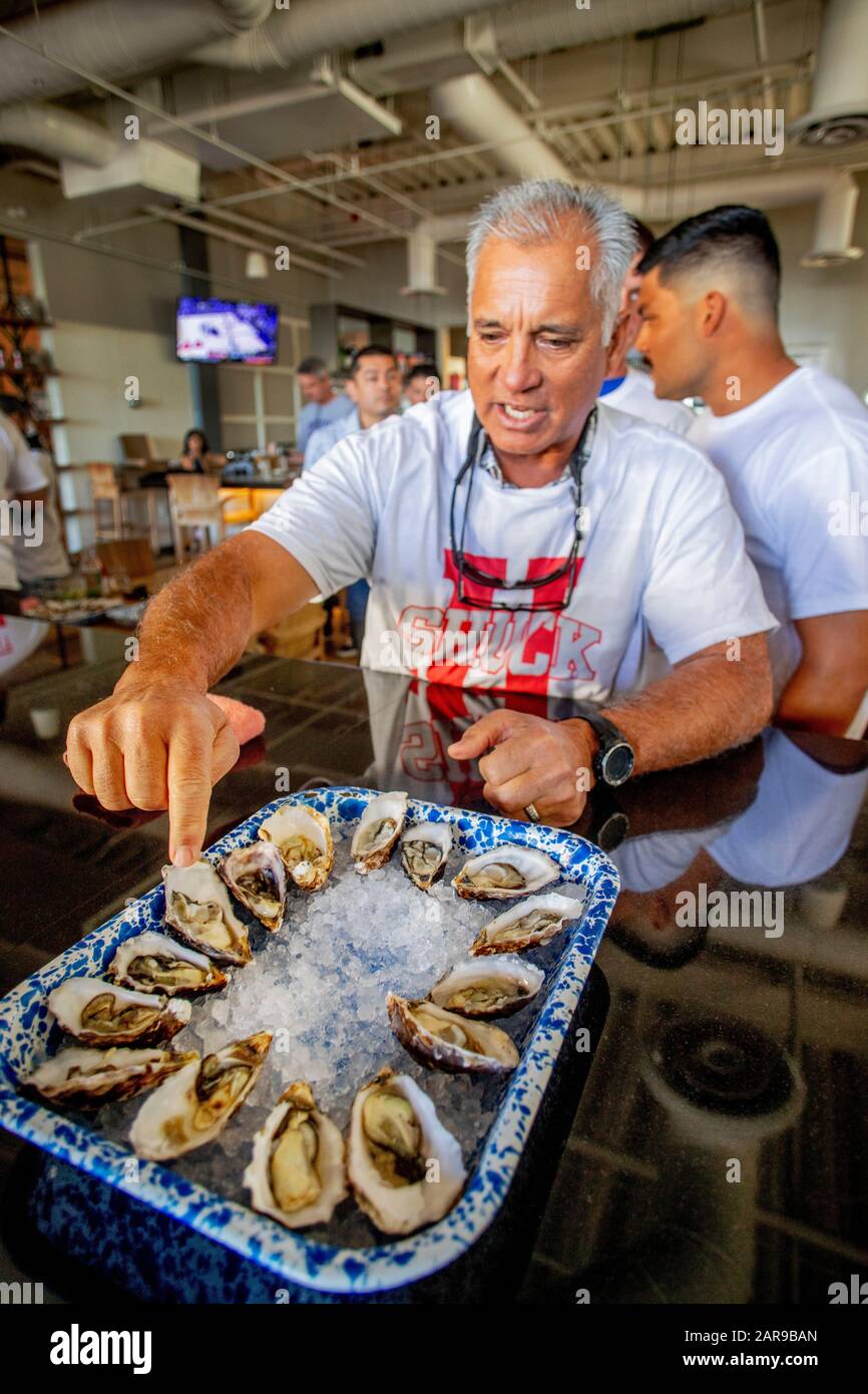 T-shirted male contestants participate in an oyster-eating contest at a ...