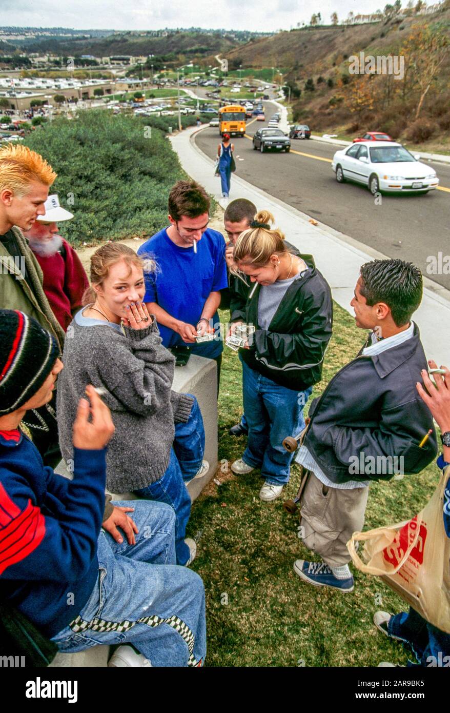 High school students smoke on the street outside their school after ...