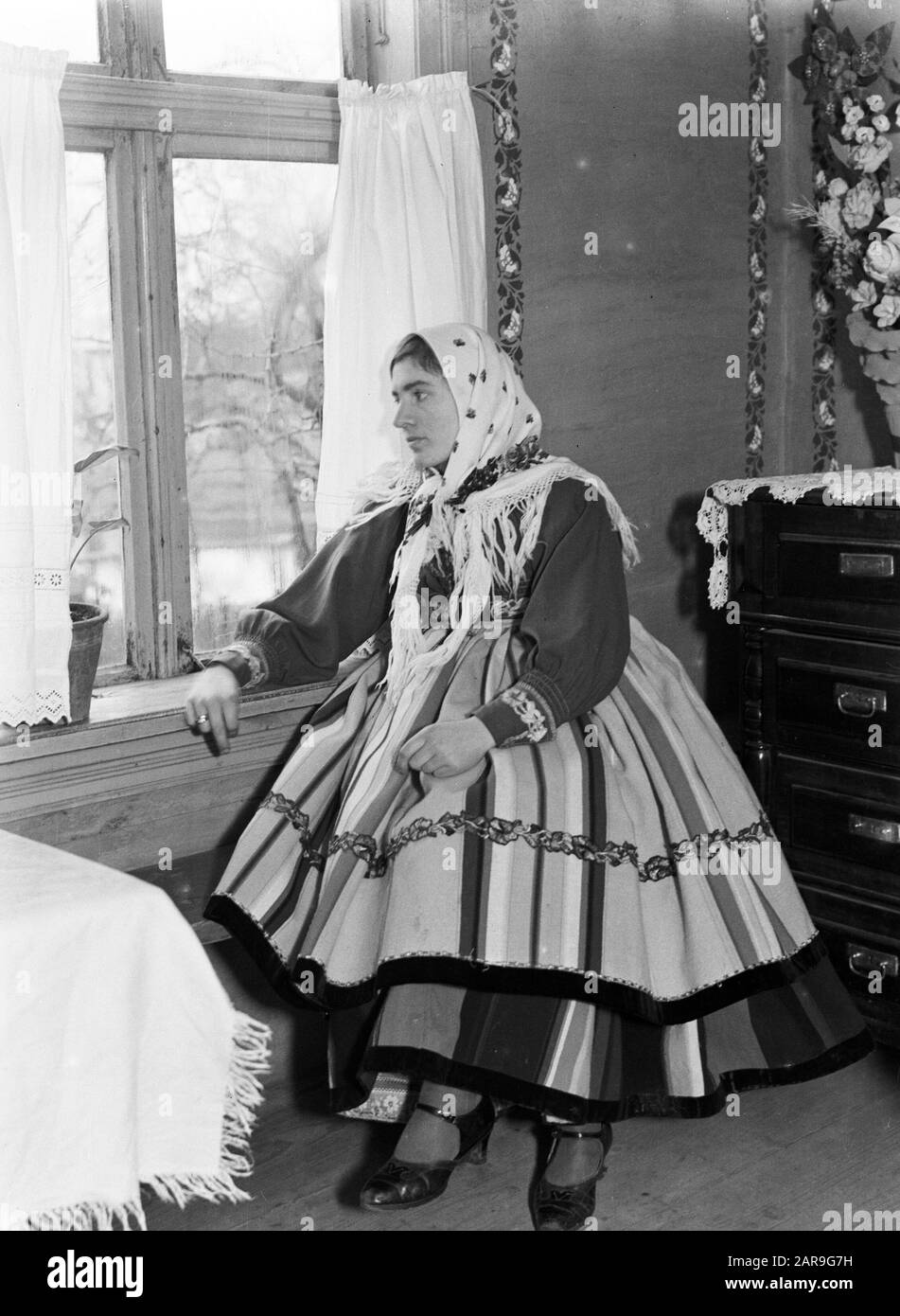 Journey to Poland Woman in traditional costume looks out the window in ...