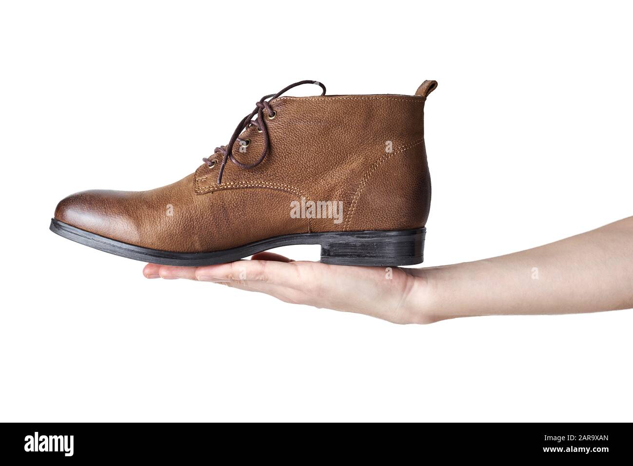 Female hand holding brown leather womens boot on white background ...