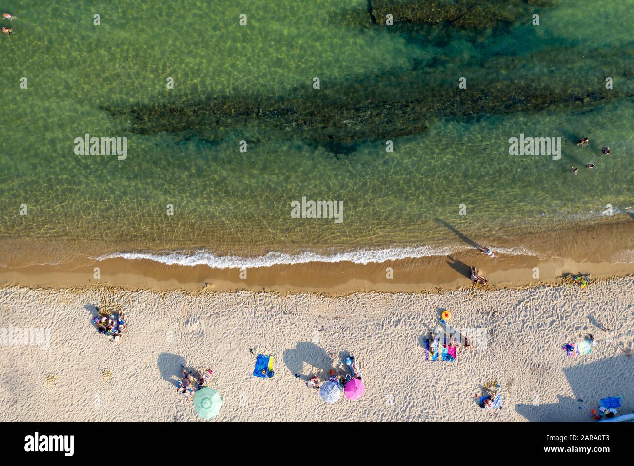 Aerial view of sandy beach with tourists swimming in beautiful clear ...