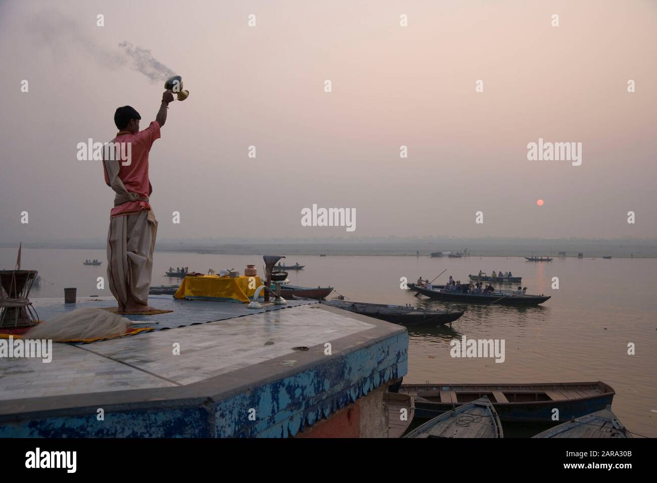 Priest perform sunrise ritual, at ghats of holy Ganges river, also ...