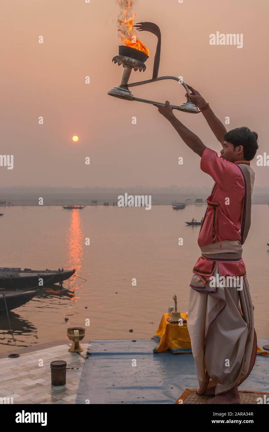 Priest perform sunrise ritual, at ghats of holy Ganges river, also ...