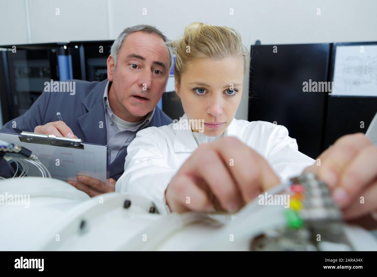 supervisor watching apprentice connecting cables Stock Photo - Alamy