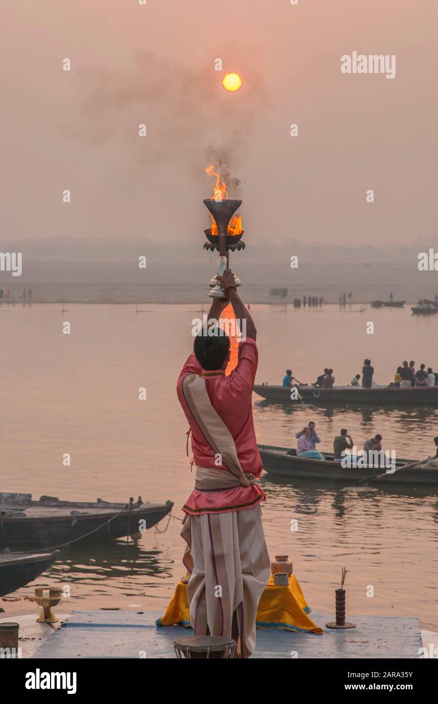Priest perform sunrise ritual, at ghats of holy Ganges river, also ...