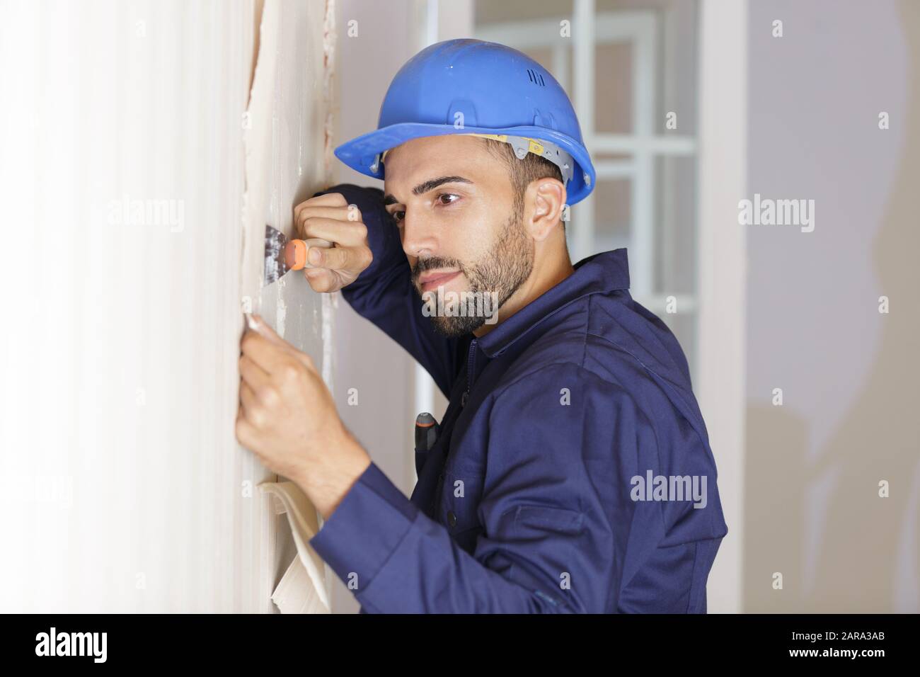 male contractor removing wallpaper in residential room Stock Photo - Alamy