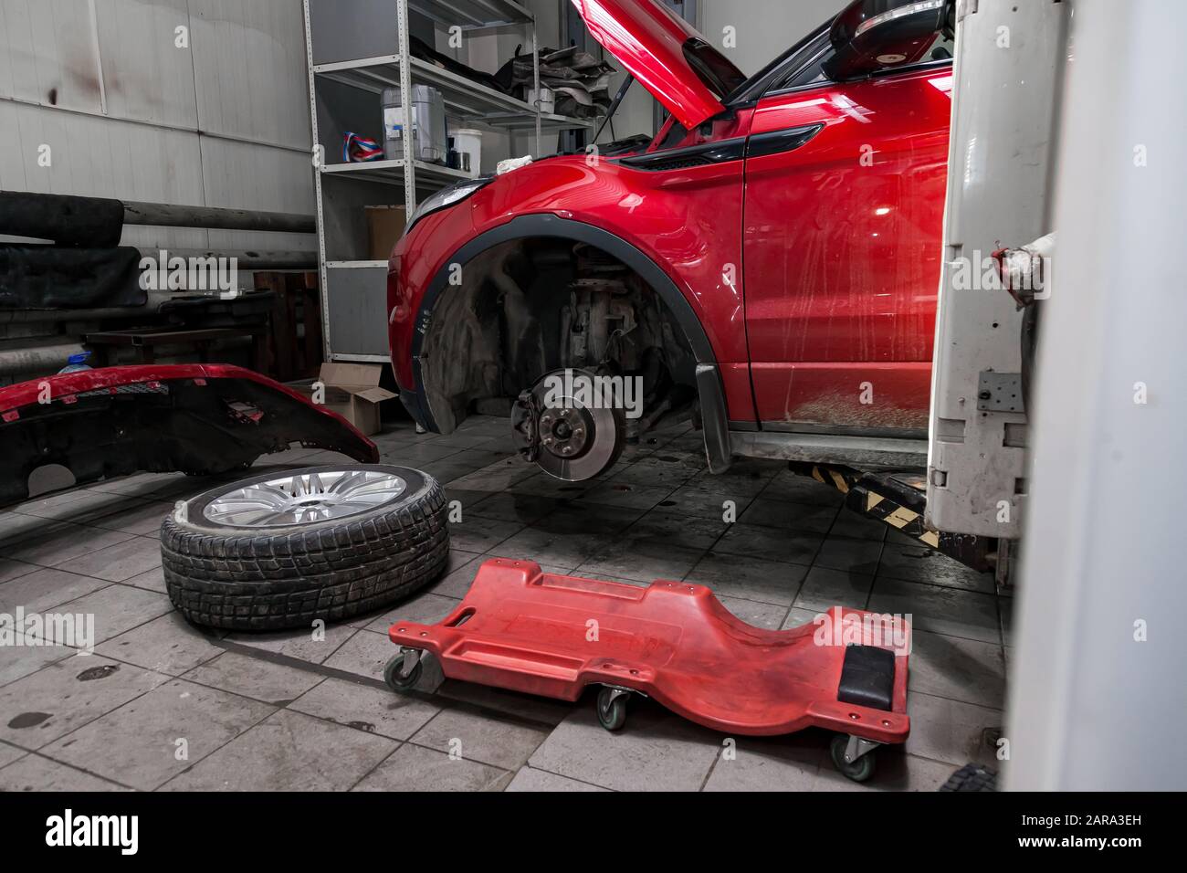 Red used car with an open hood raised on a lift for repairing the ...