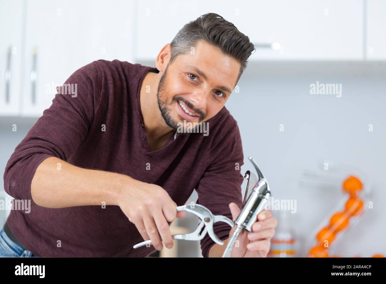 happy man fixing tap with tool in the kitchen Stock Photo - Alamy