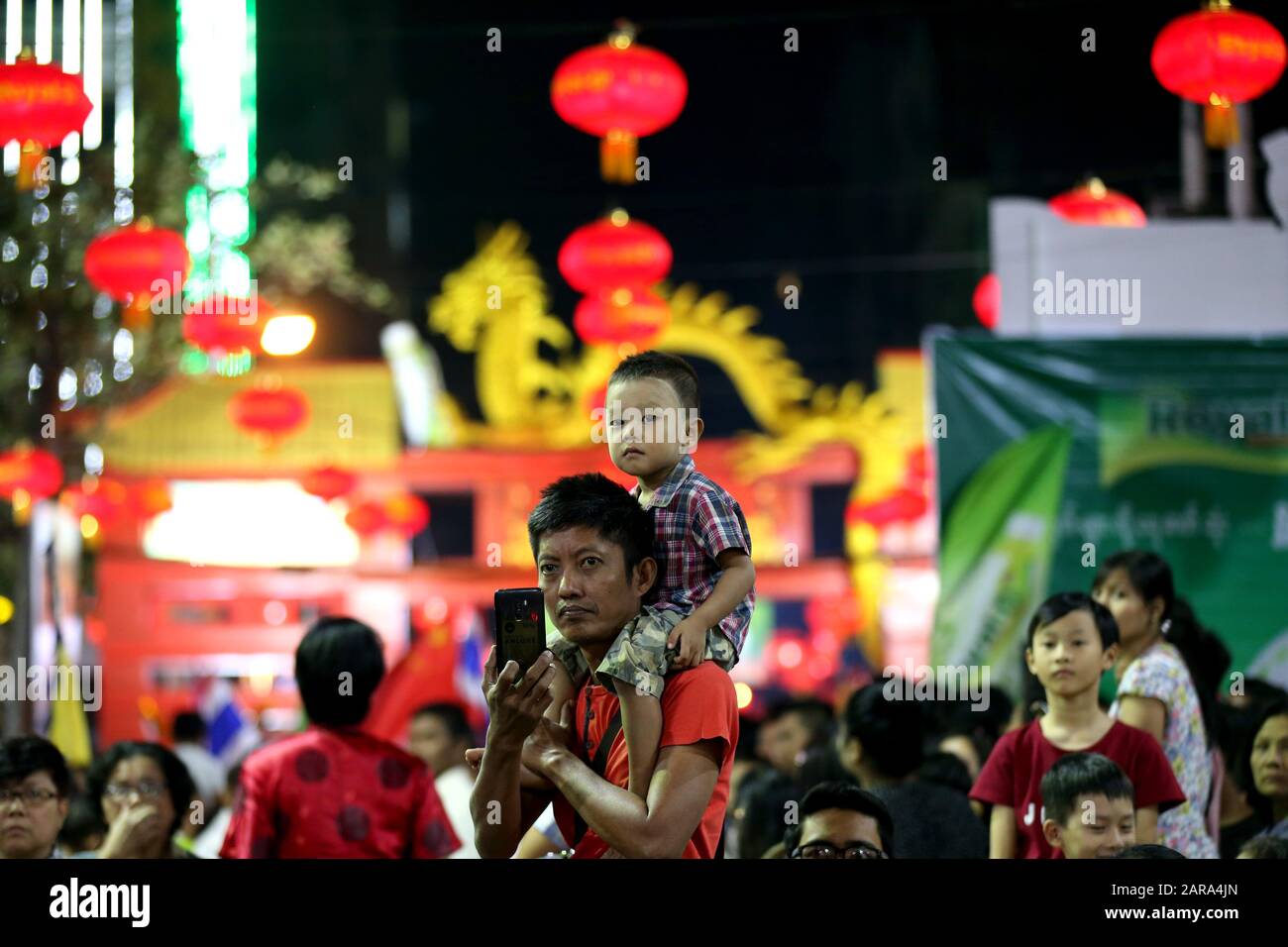 Yangon, Myanmar. 26th Jan, 2020. A boy sits on his father's shoulders ...