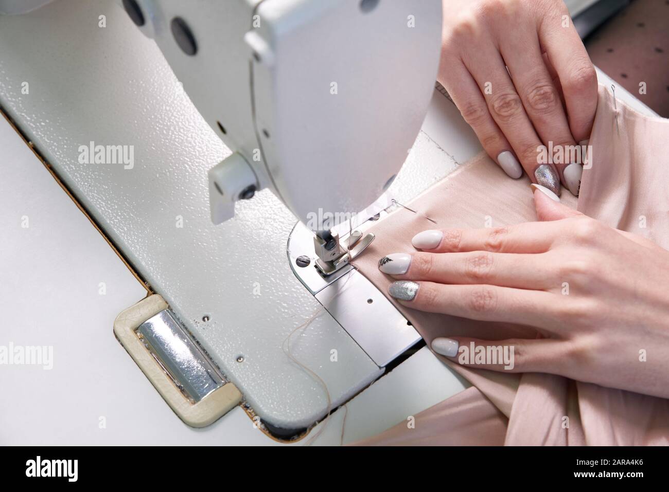 Woman using sewing machine in tailor studio or modern atelier shop ...