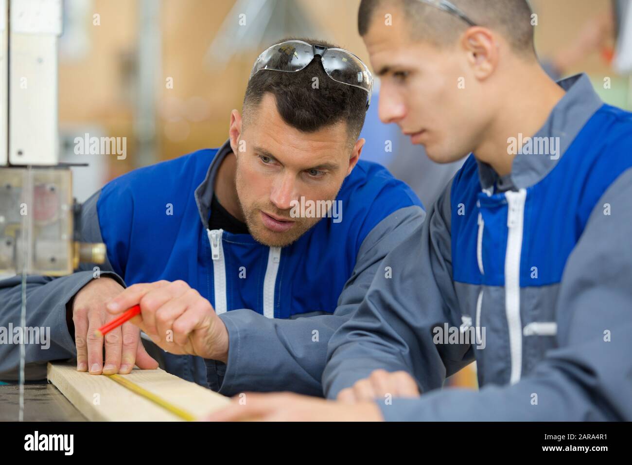 apprentice watching tutor using bench saw Stock Photo - Alamy