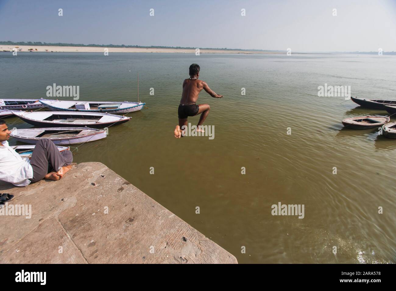 Young boy diving to Ganges river at holy ghats, also Ganga river ...