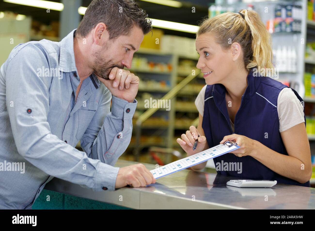 sales assistant dealing with customer over shop counter Stock Photo - Alamy