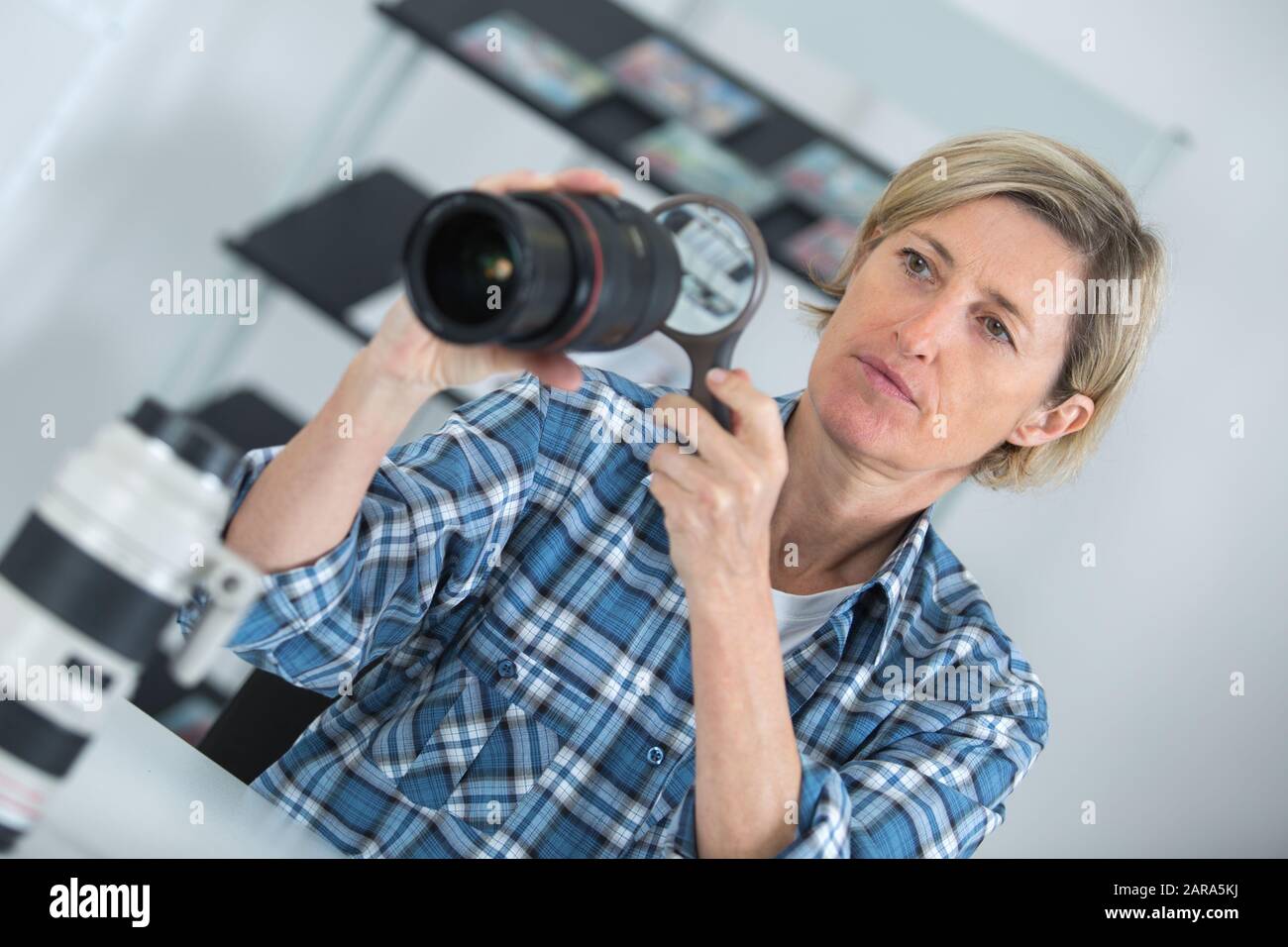 female photographer checking camera with magnifying glass Stock Photo ...