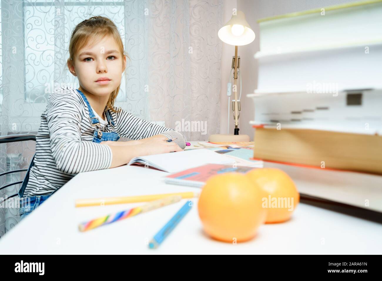 Teenage girl doing homework at table Stock Photo - Alamy