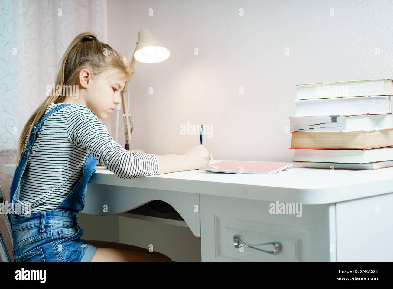 Teenage girl doing homework at table Stock Photo - Alamy
