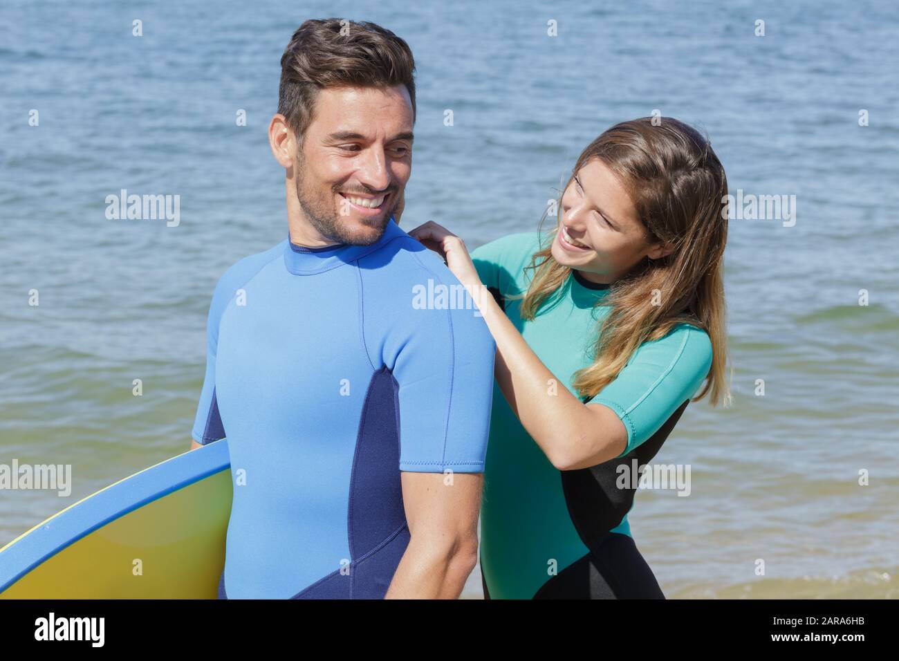 lady zipping up the back of mans wetsuit Stock Photo - Alamy