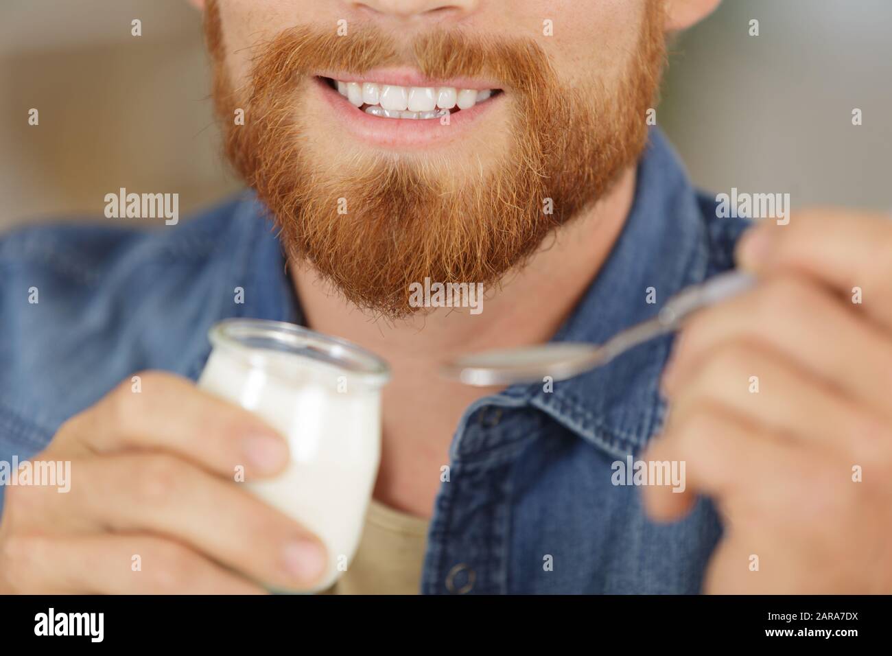 a young man eating yogurt Stock Photo - Alamy