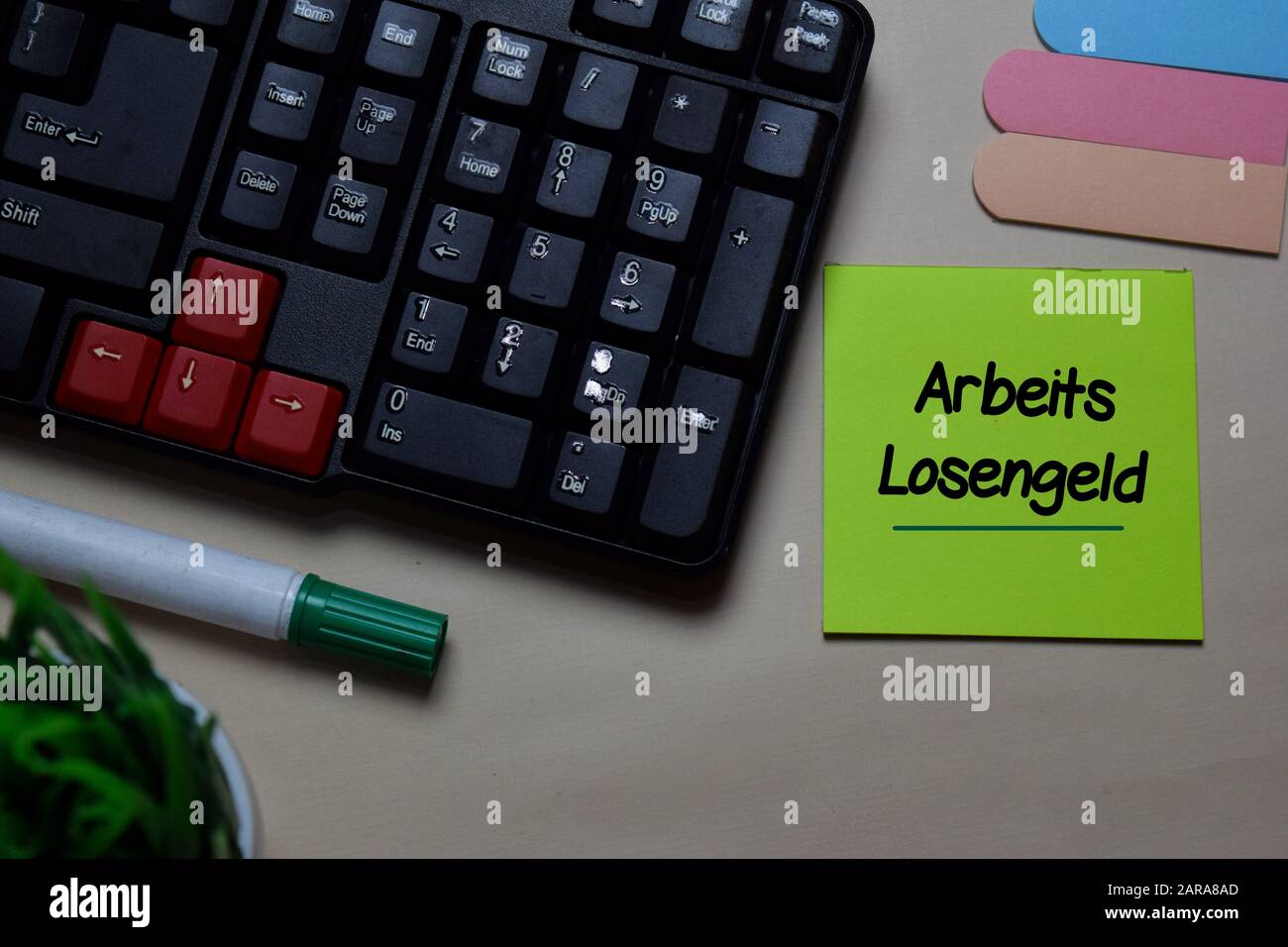 Arbeitslosengeld write on a sticky note isolated on office desk. German ...