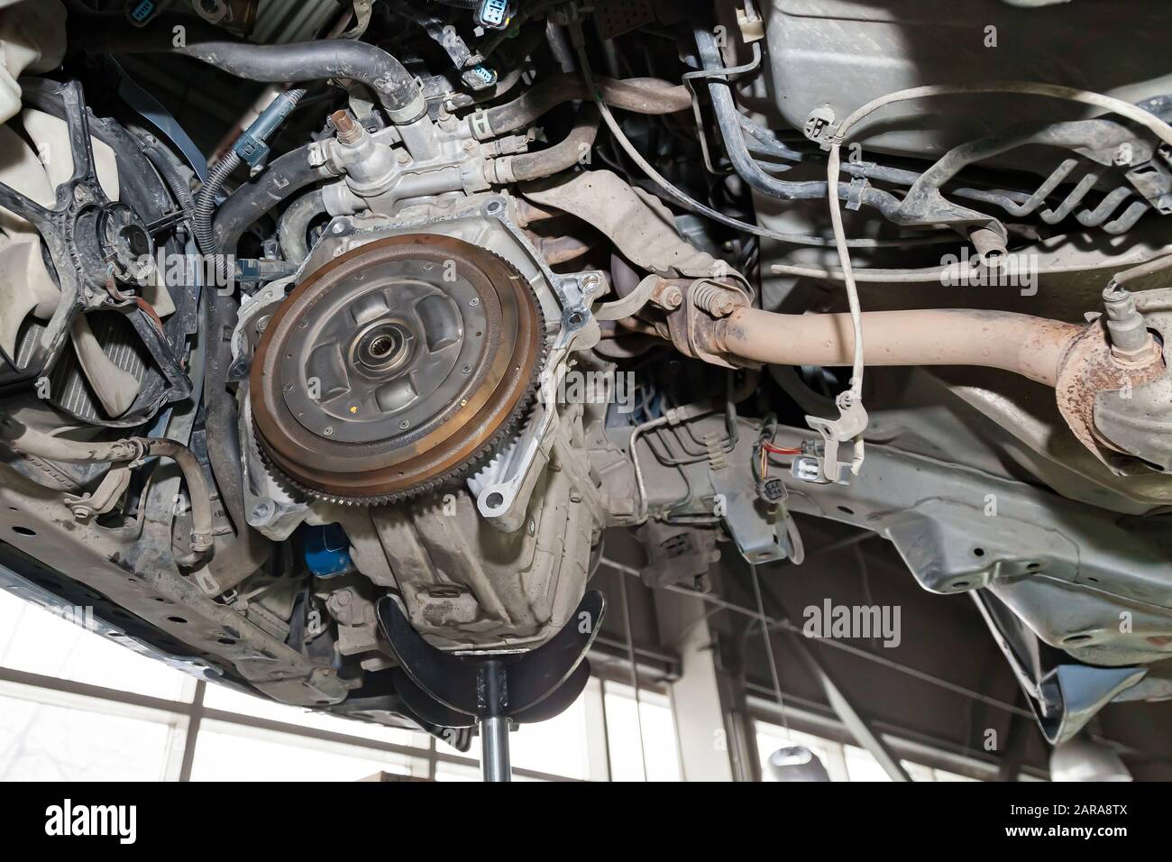 A car raised on a lift for repair and under it a detached Transmission ...