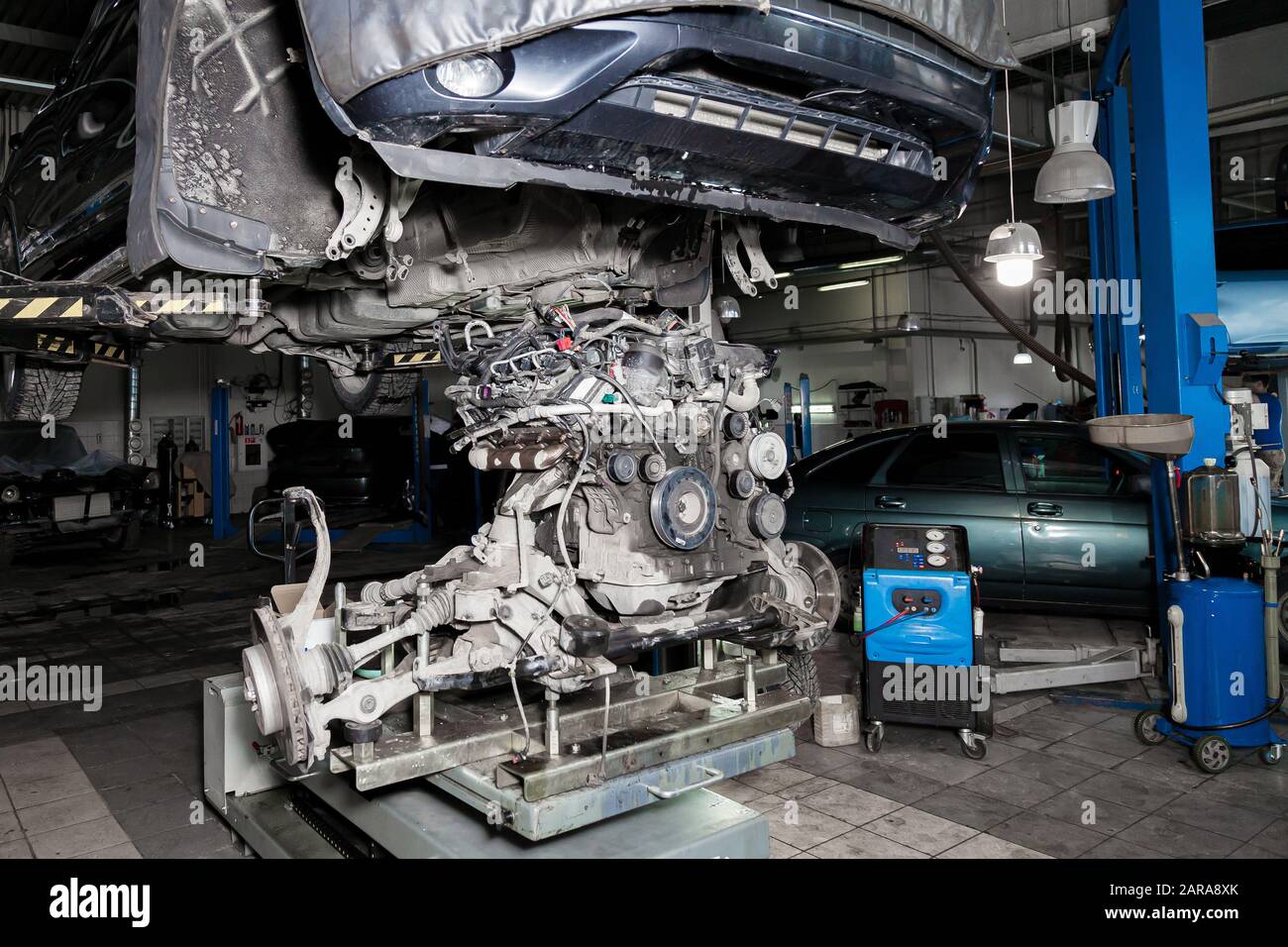 Replacement used engine on a table mounted under raised car on lift for ...