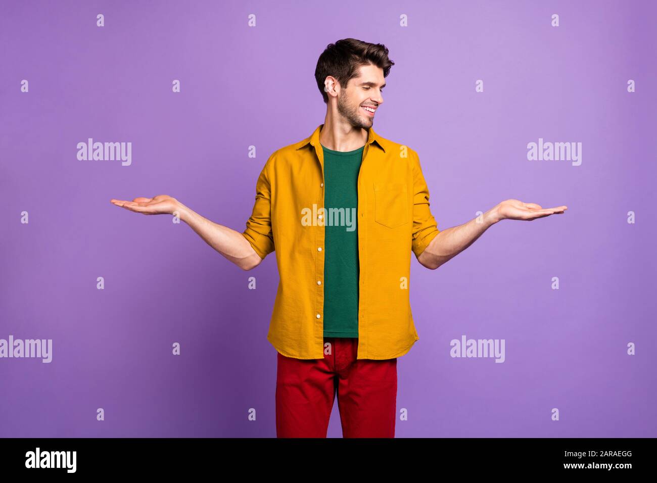 Photo of cheerful white man holding two objects empty space with hands ...