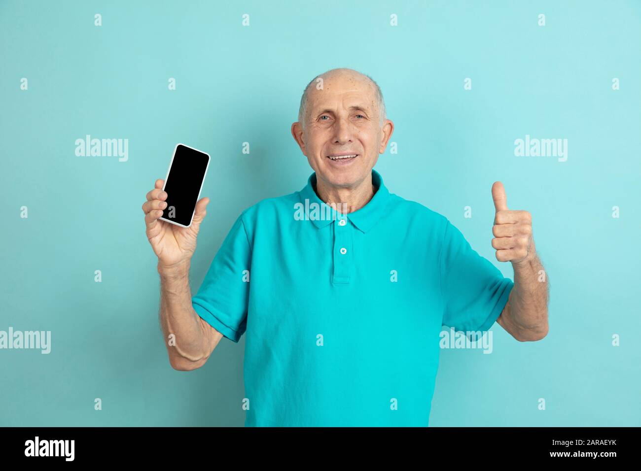 Showing blank phone's screen. Caucasian senior man's portrait on blue ...