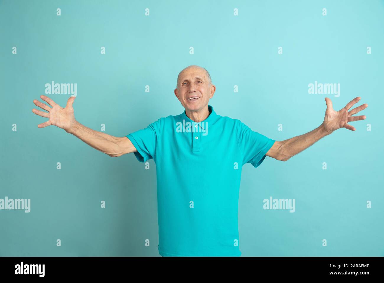 Greeting, inviting. Caucasian senior man's portrait isolated on blue ... Greeting, inviting. Caucasian senior man's portrait isolated on blue ...