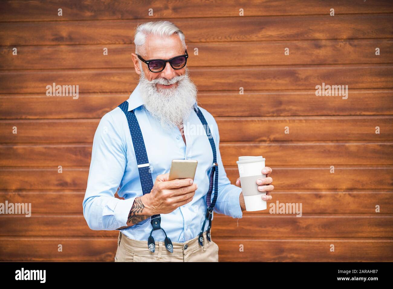 Happy senior man using smartphone app outdoor with wood background ...