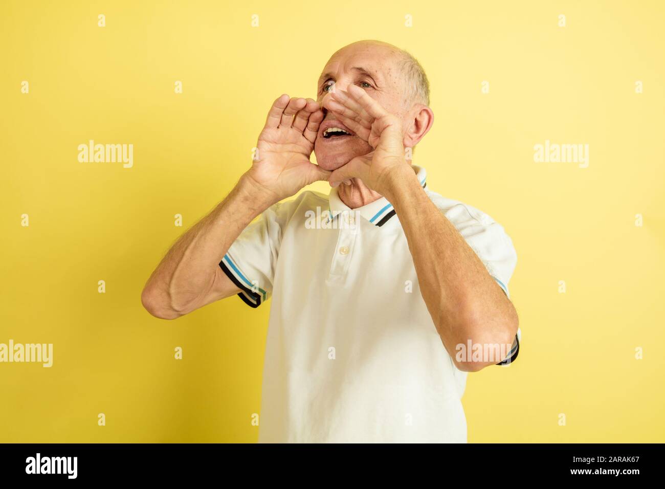 Calling somebody. Caucasian senior man's portrait isolated on yellow ...