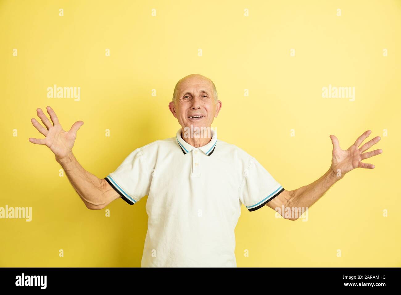 Greeting, inviting. Caucasian senior man's portrait isolated on yellow ...