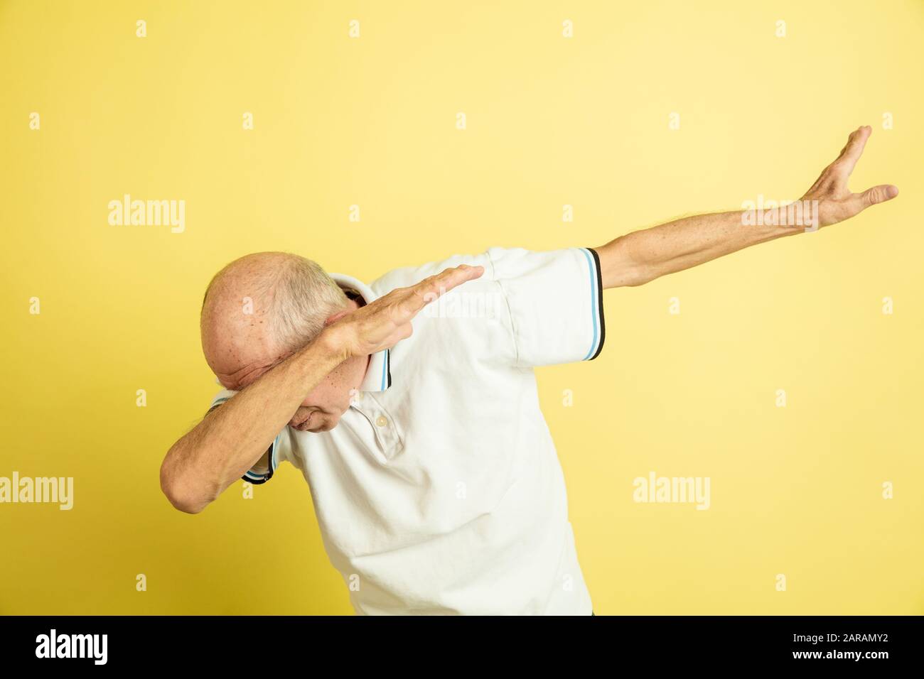 Dabbing, dab. Caucasian senior man's portrait isolated on yellow studio ...