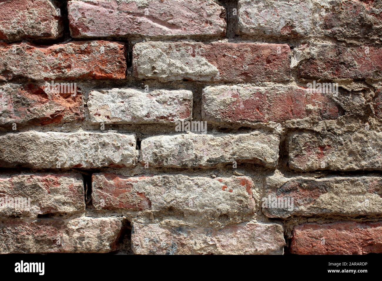 Cracked dilapidated suburban family house wall made of red bricks partially covered with ...