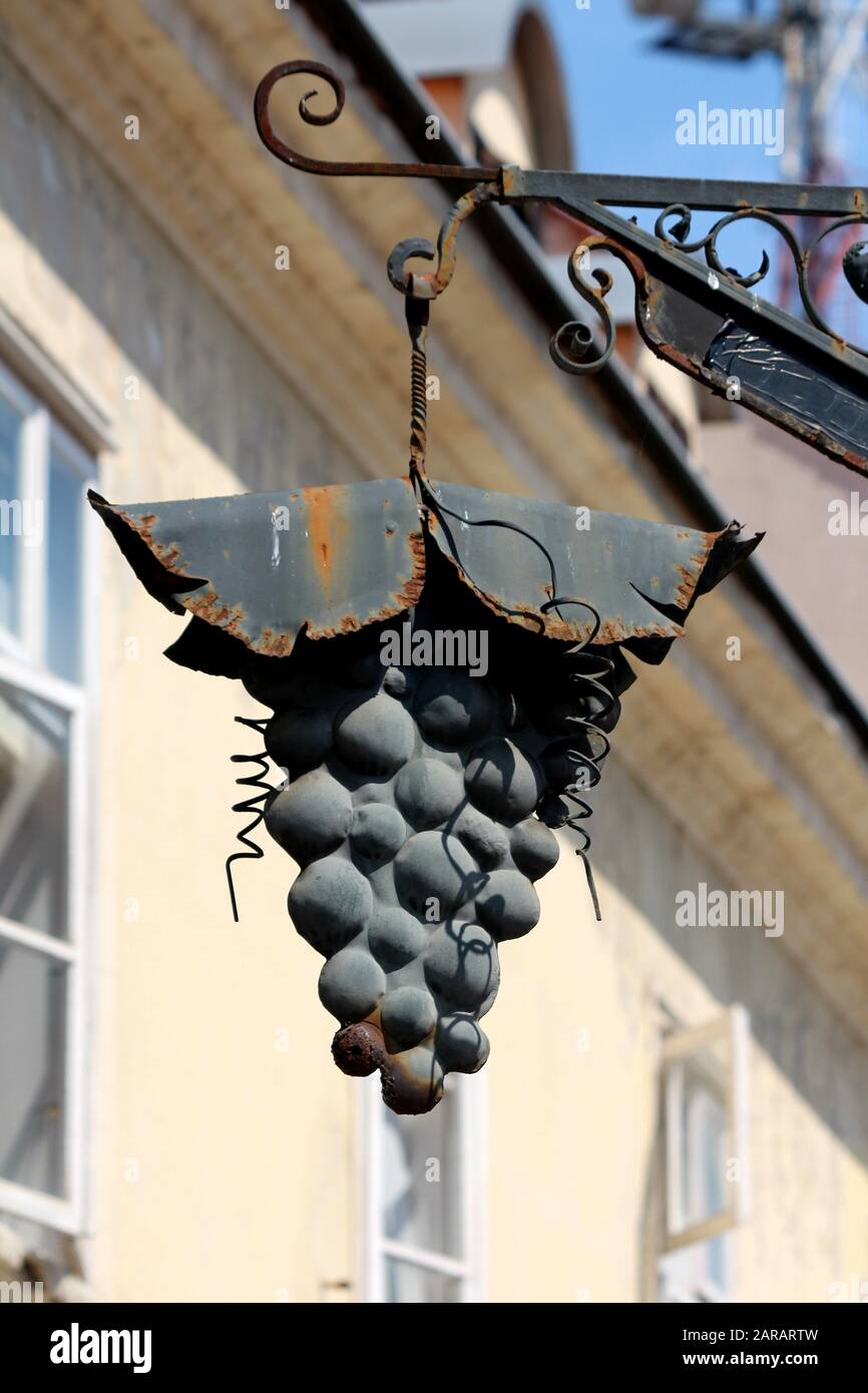 Grape like partially rusted dark wrought iron sign mounted on side of ...