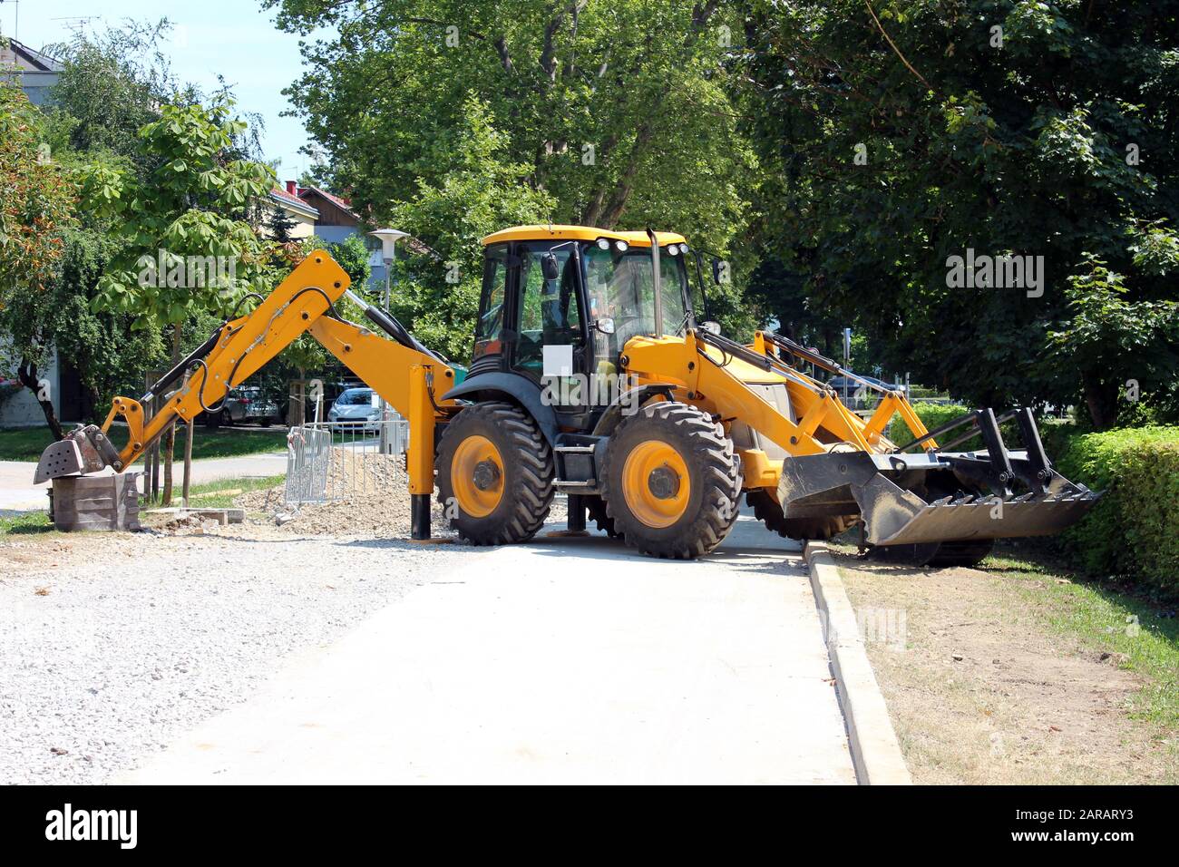 Large industrial backhoe loader parked across local road to prevent ...